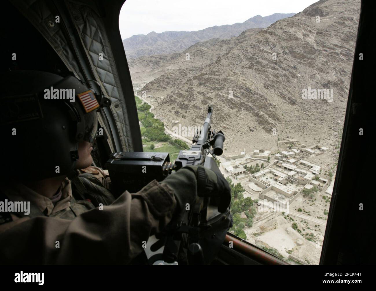 A U.S. machine gunner looks out of a chopper as troops and materials ...