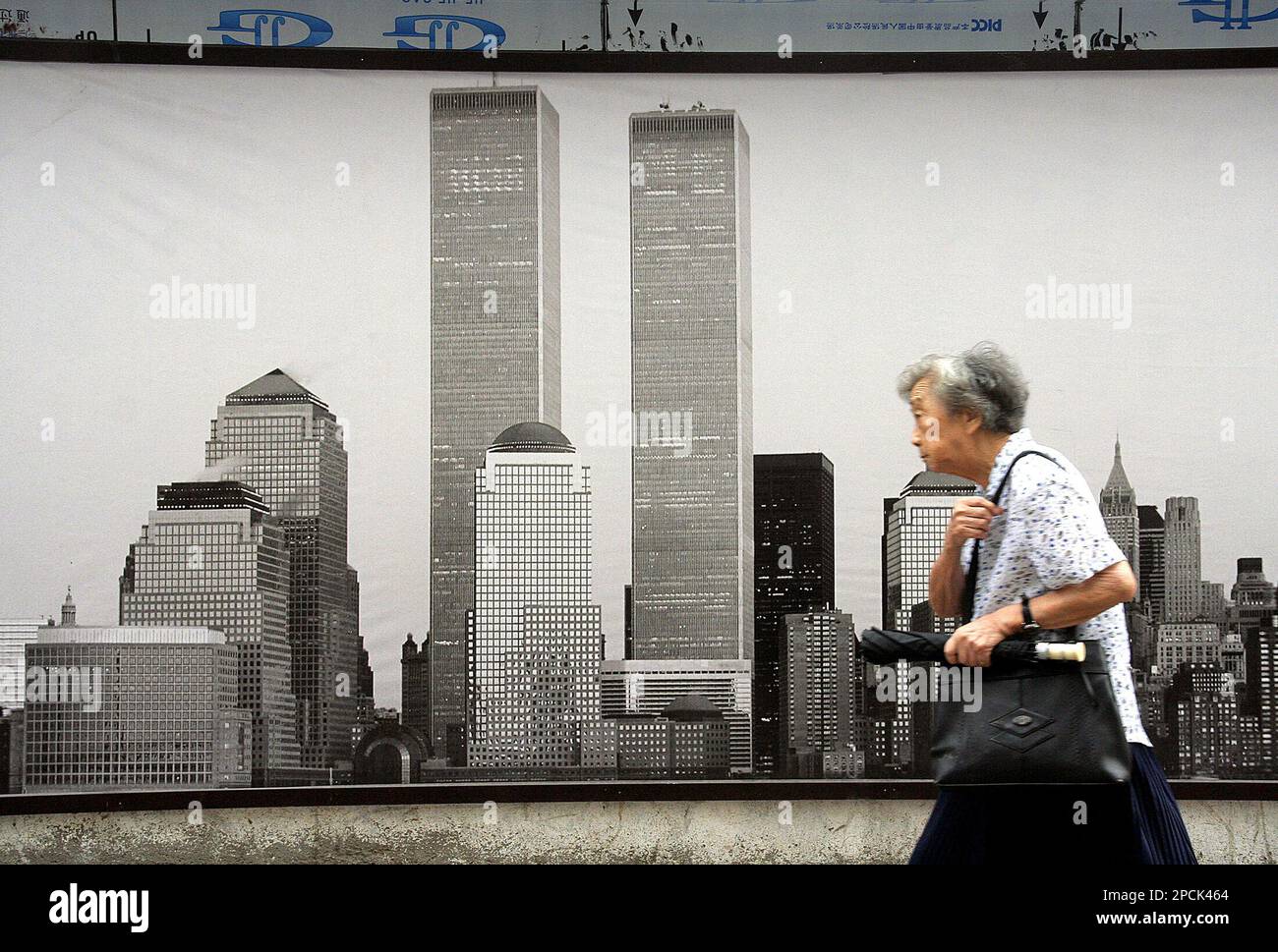A Chinese woman walks past an advertisement for a new building under ...