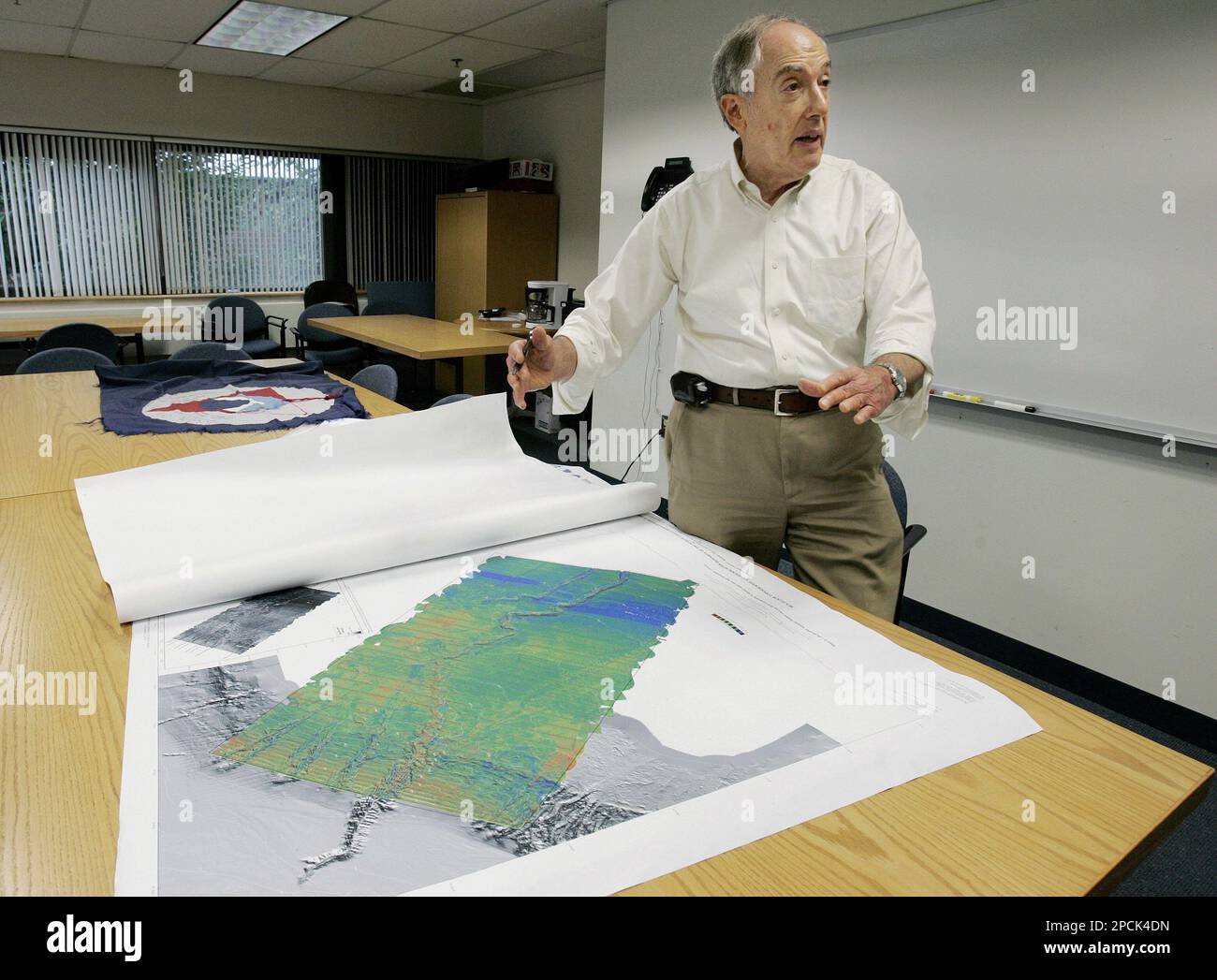 Professor Peter A. Rona stands near computer-generated maps showing the ...