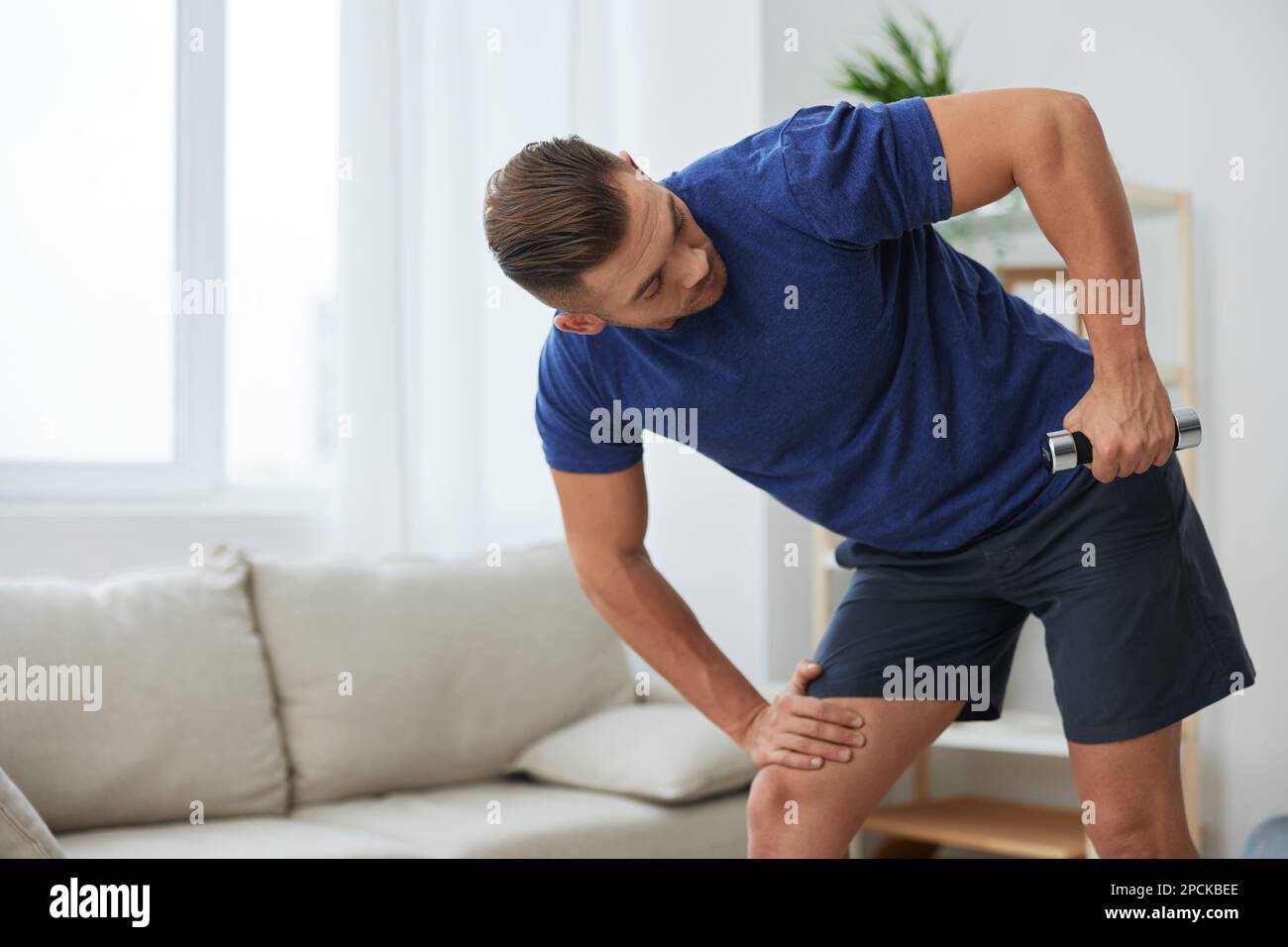 Man sportsman training at home with dumbbells, exercises for arms and ...