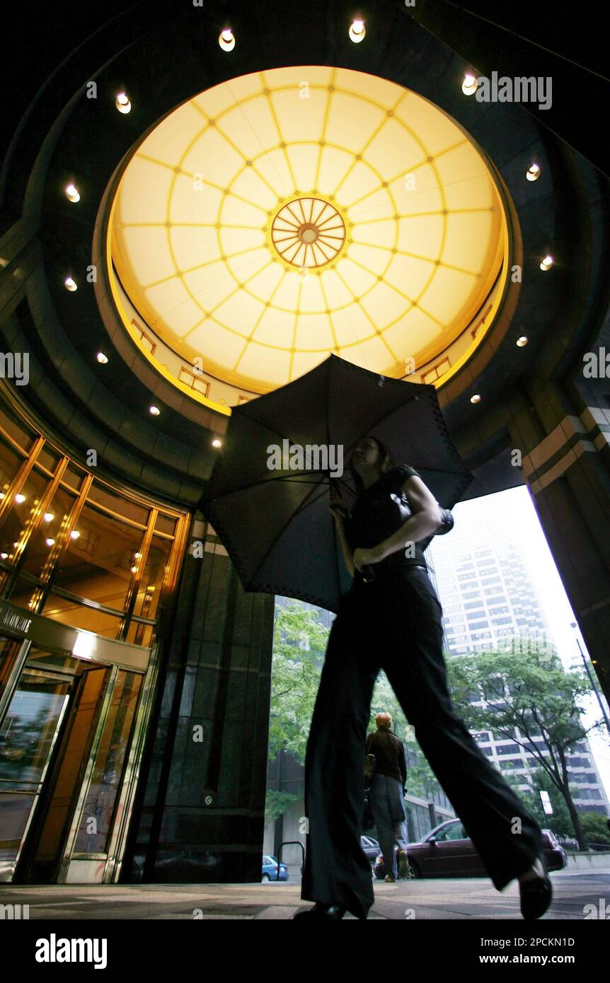 A pedestrian walks under the overhang of a high-rise office building ...