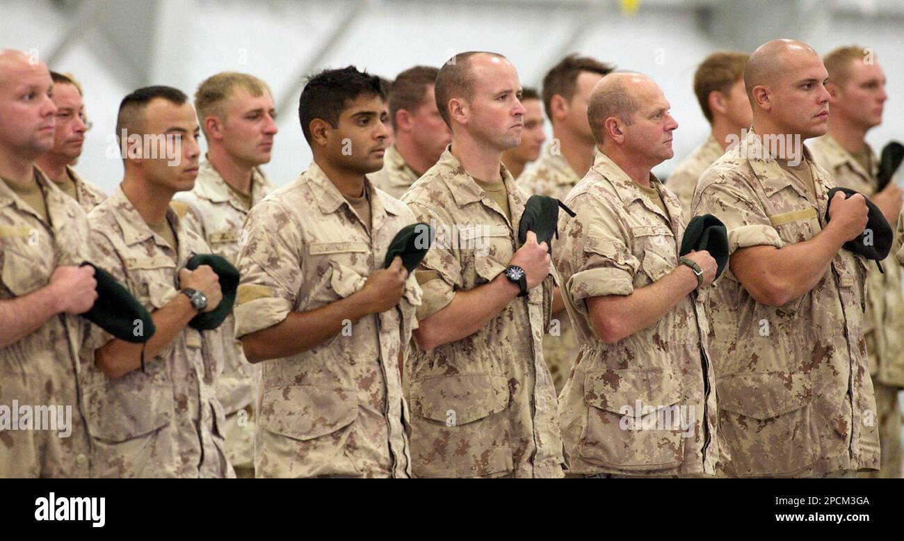 Soldiers stand with their berets over their hearts, on Friday, Aug. 25 ...