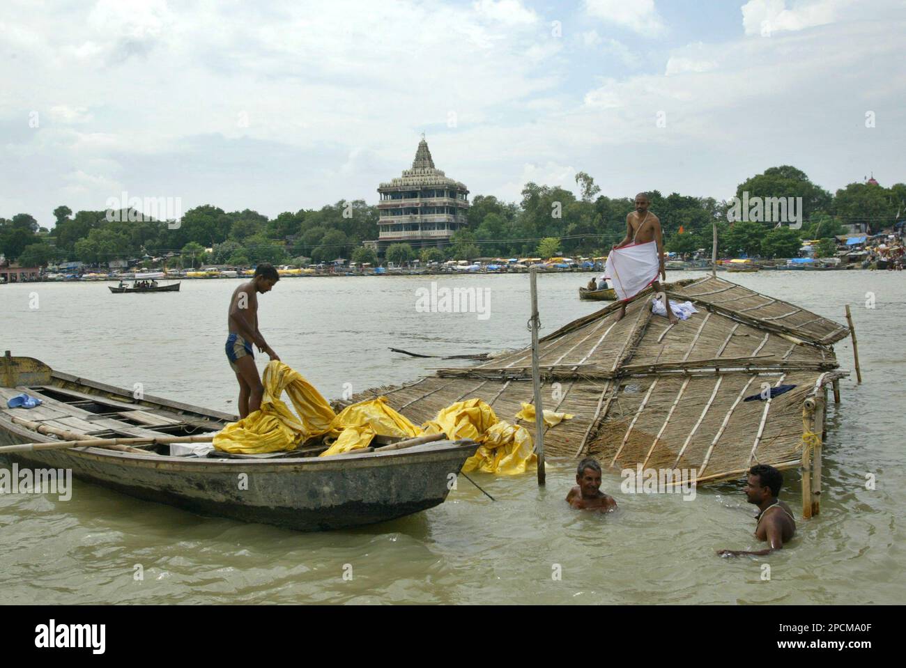 People dismantle submerged huts on the banks of the flooded River ...