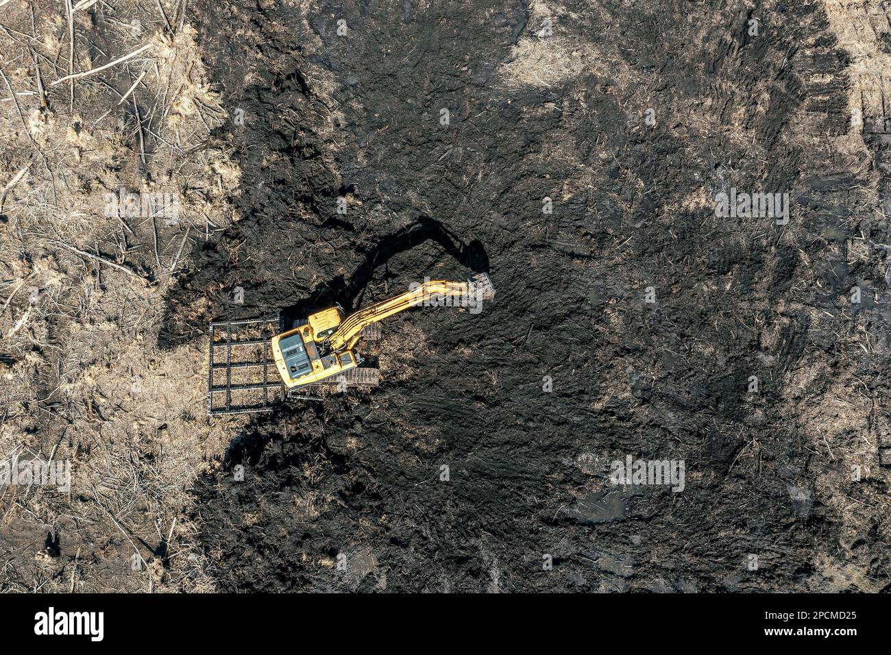 yellow working excavator digging black soil or peat. aerial top view ...