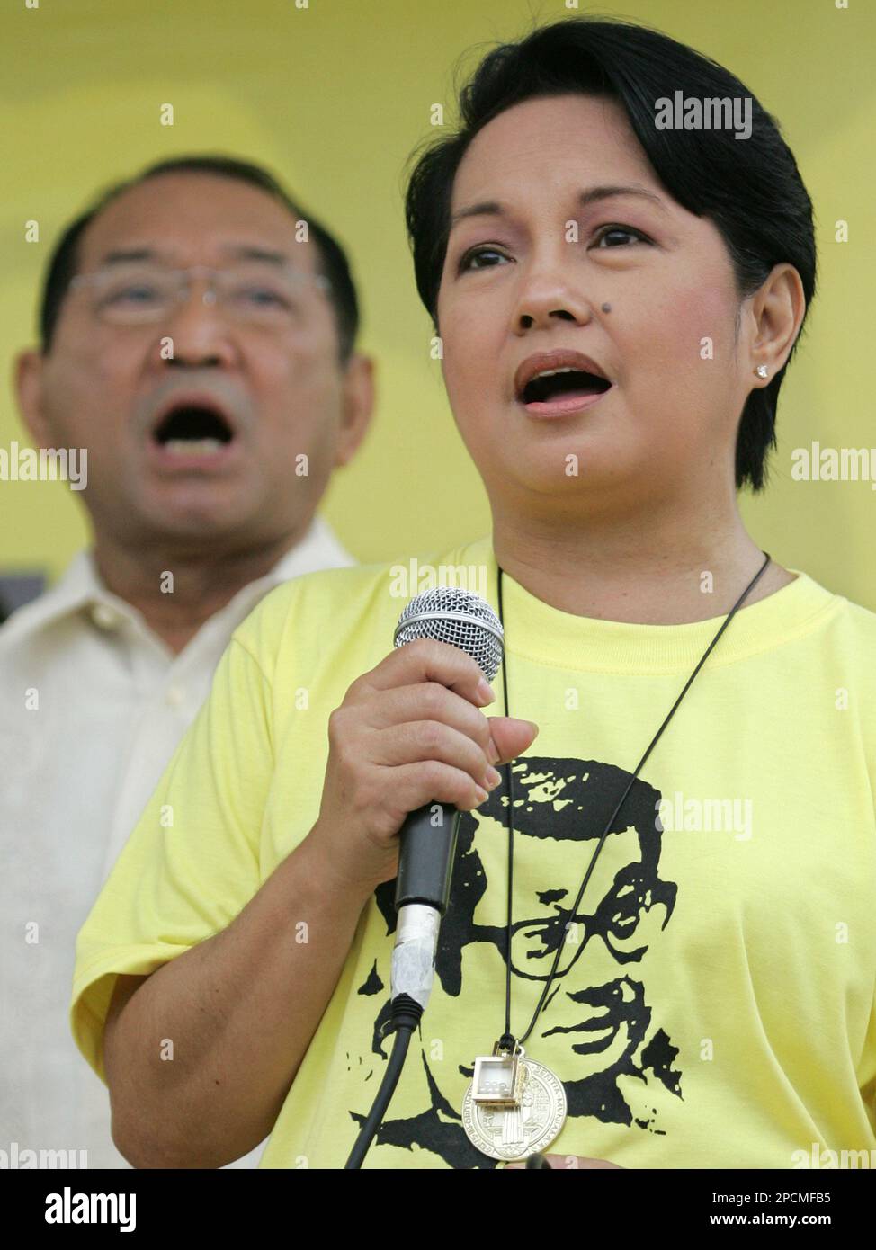 Philippine President Gloria Macapagal Arroyo, right, wearing a shirt bearing an image of Benigno ...