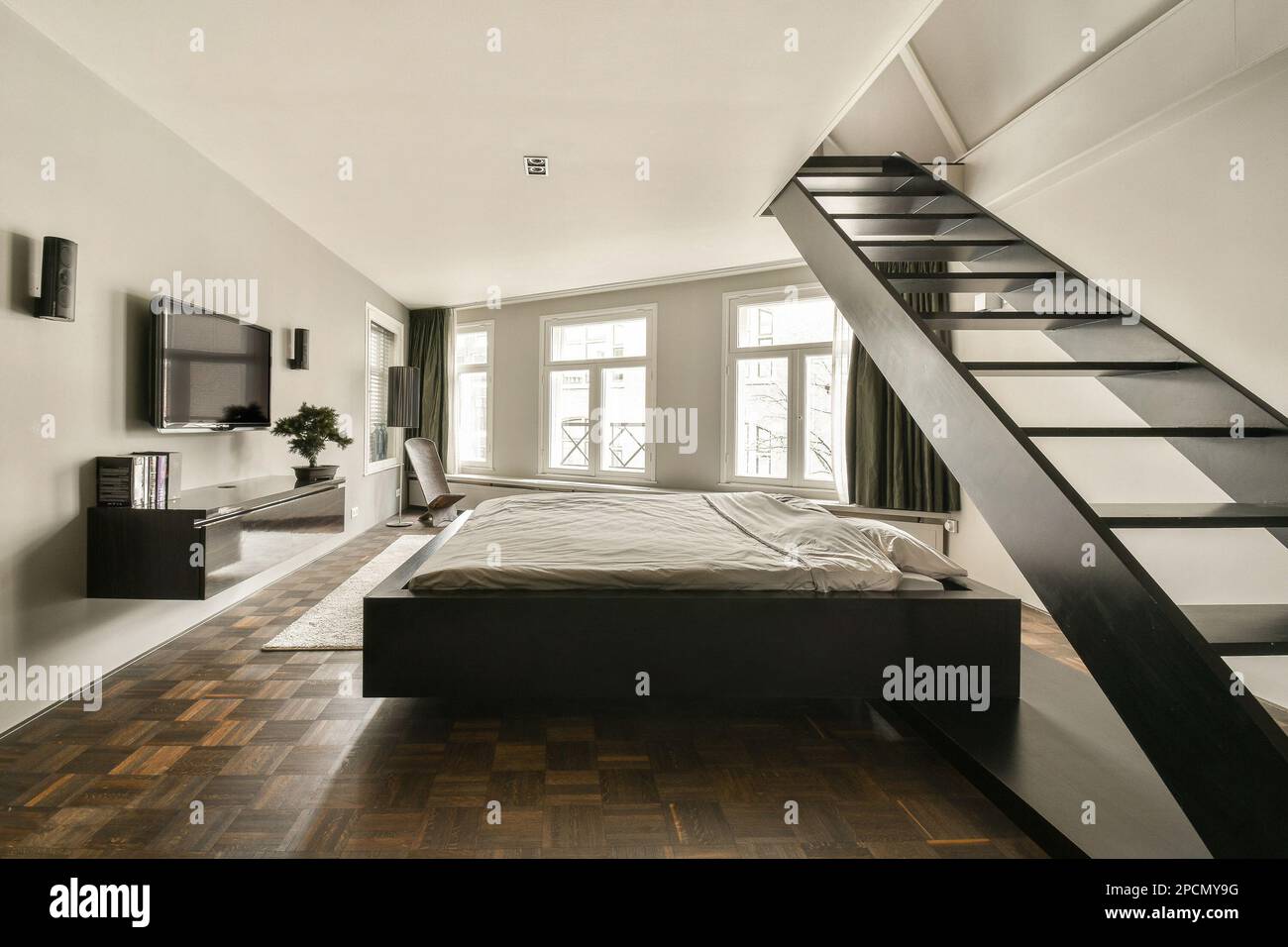 a bedroom with stairs leading up to the bed and an entertainment unit ...