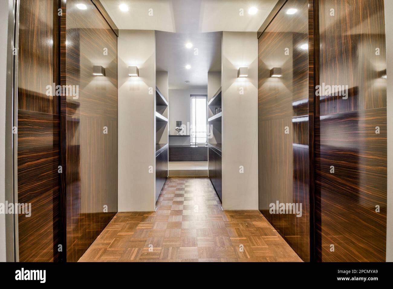 a long hallway with wood flooring and white walls on both sides ...