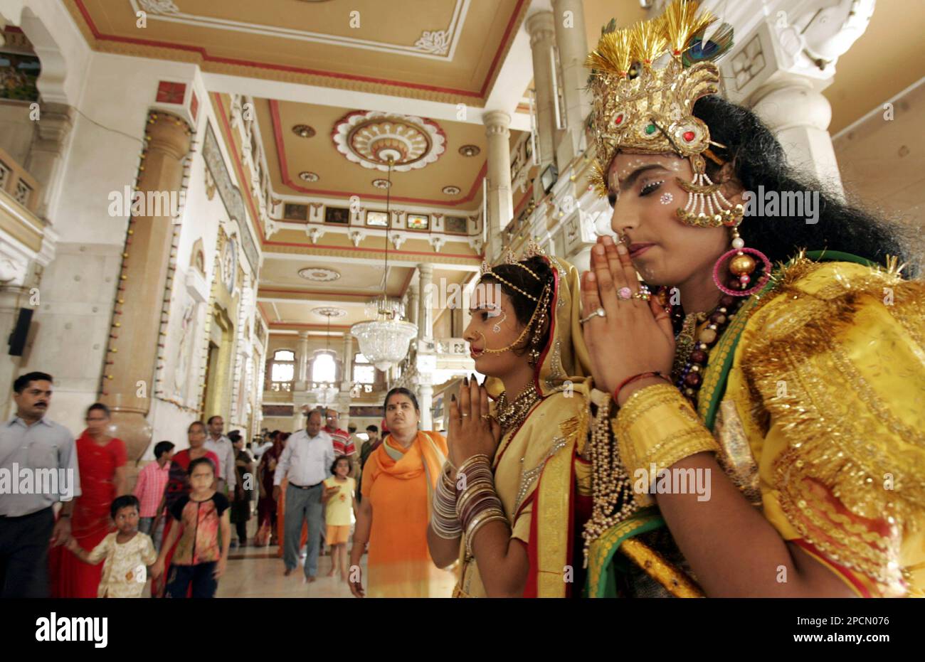 A young devotee dressed as Lord Krishna prays during the birthday ...