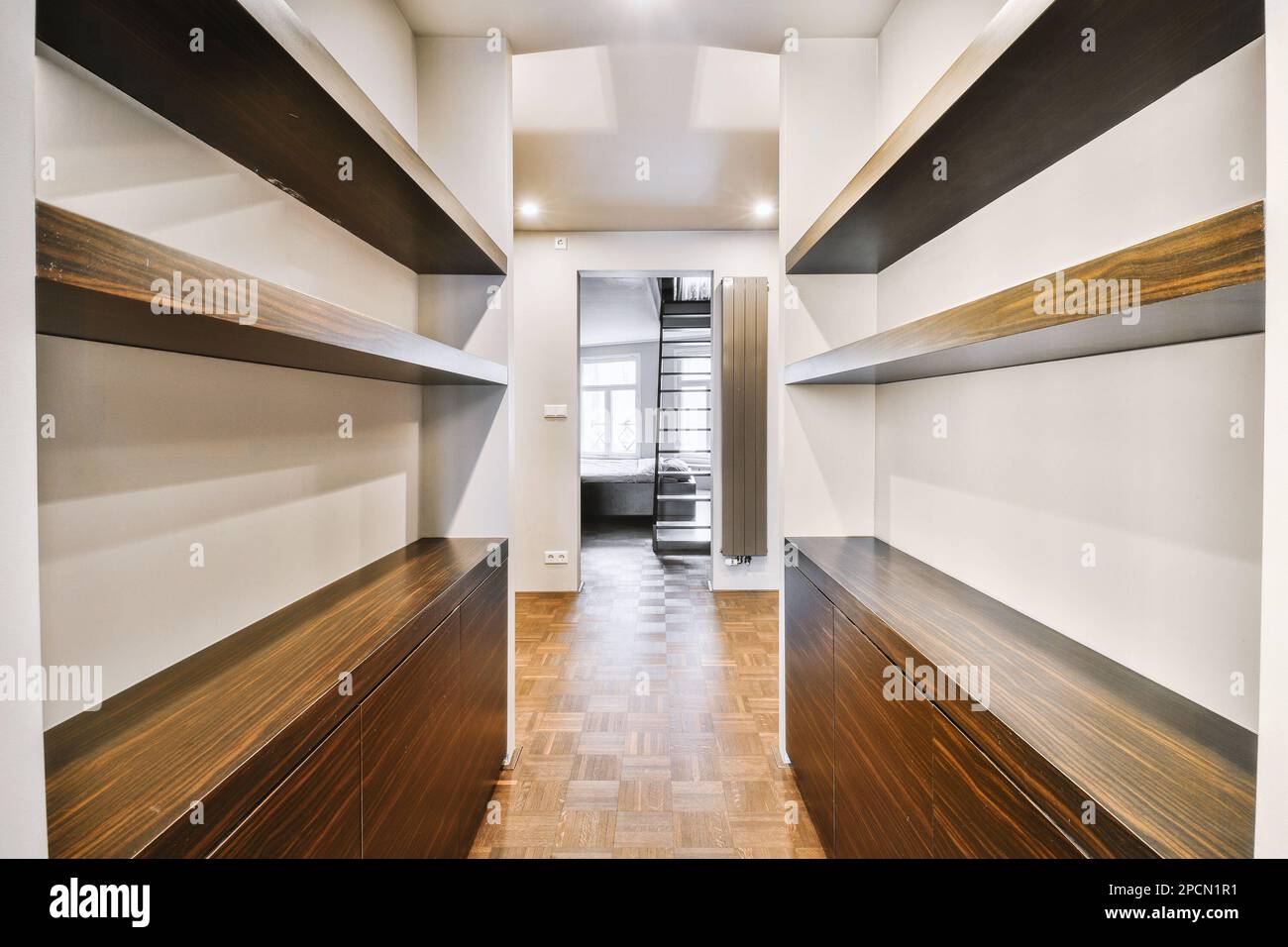 a long narrow hallway with wood flooring and white walls on either side by the wall is an open ...