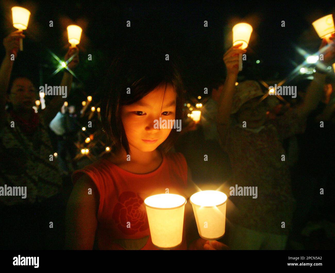 A Japanese girl holds lit candles as she joins a candlelight vigil to ...