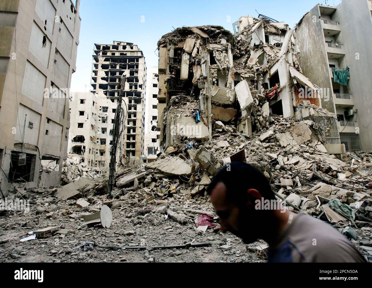 A Lebanese Shiite walks past destroyed apartment building in the ...