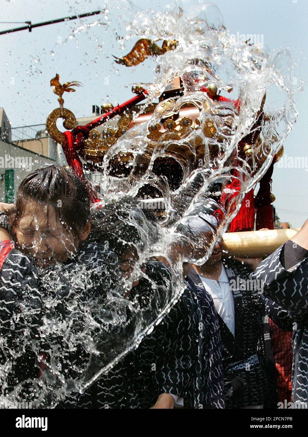 Japanese festival goers carrying a portable shrine parade through a ...