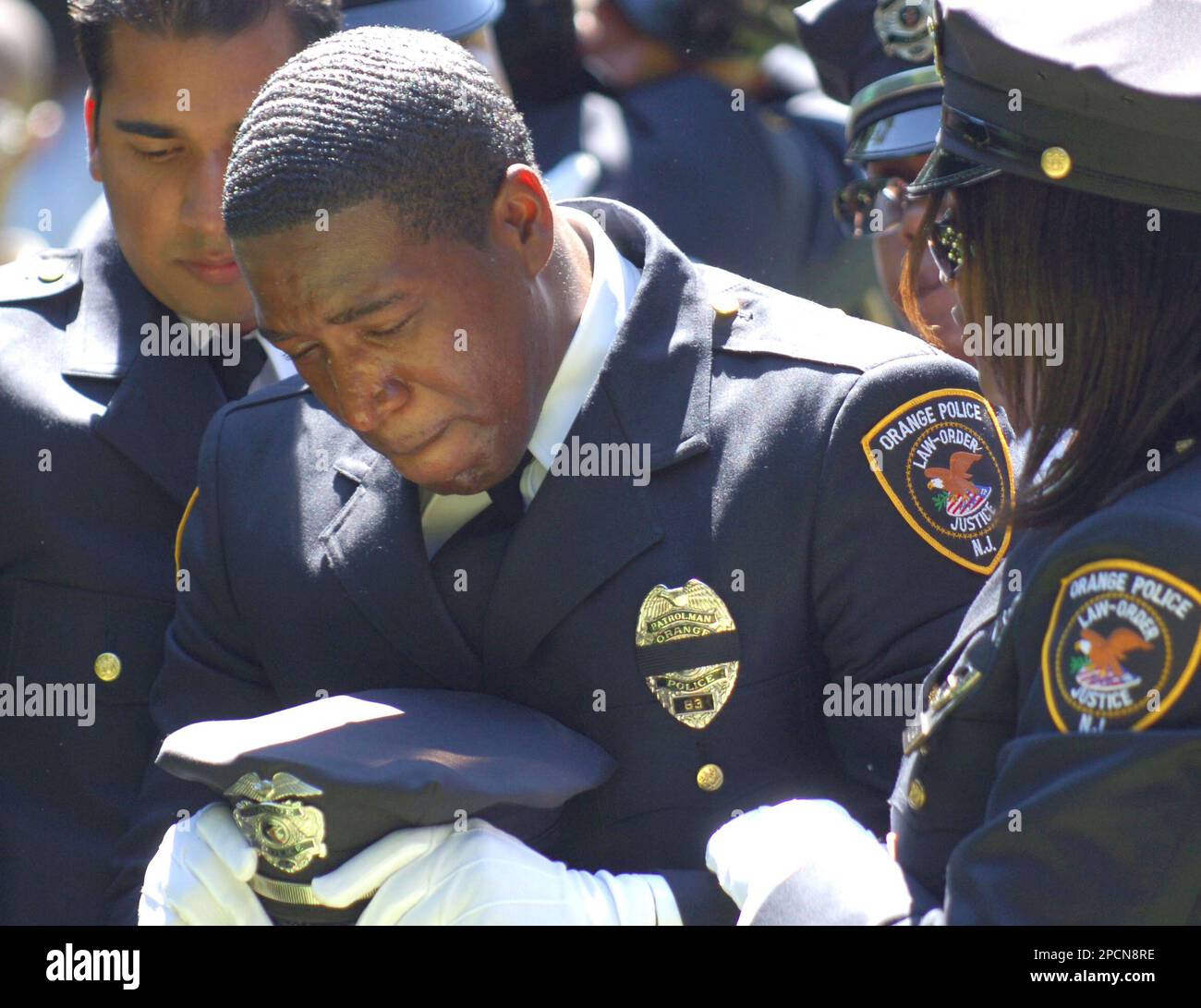 Orange police officers console each other during the funeral for ...