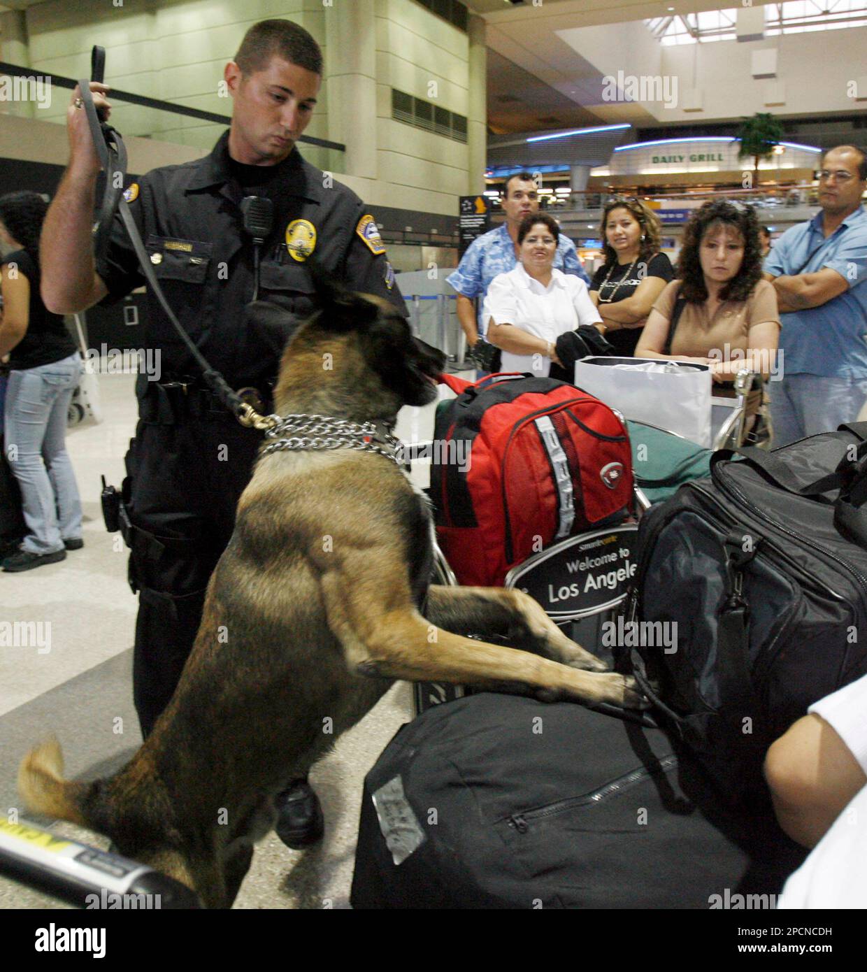 Los Angeles Airport Police officer Michael Manahan guides his dog, Baso ...