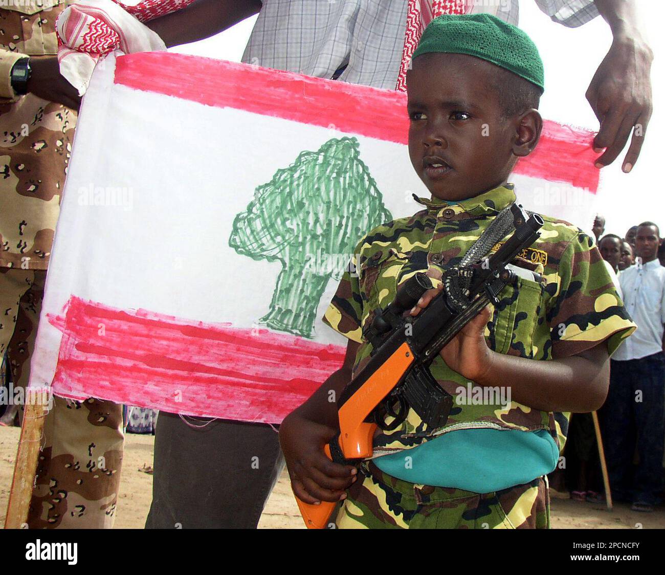 A Somali boy poses with a toy gun in front of a home made Lebanese flag ...