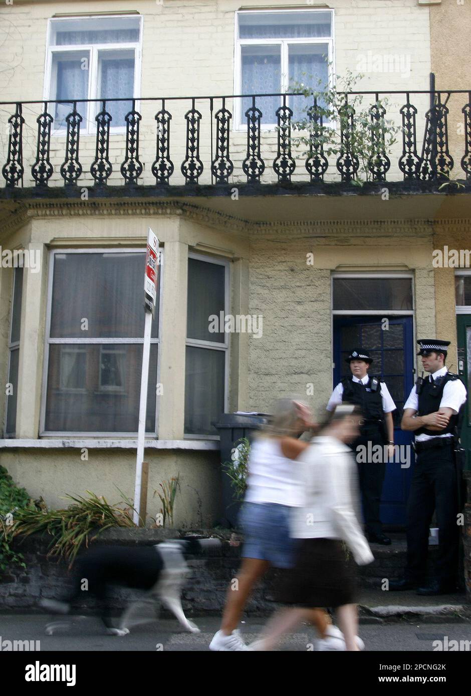 Unidentified women walk past as police officers, right, stand outside a ...