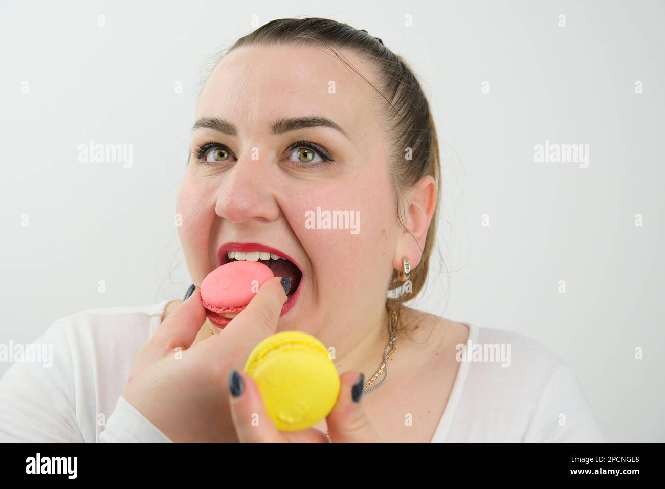 chubby fat woman quickly eats macaroons red lipstick white background ...