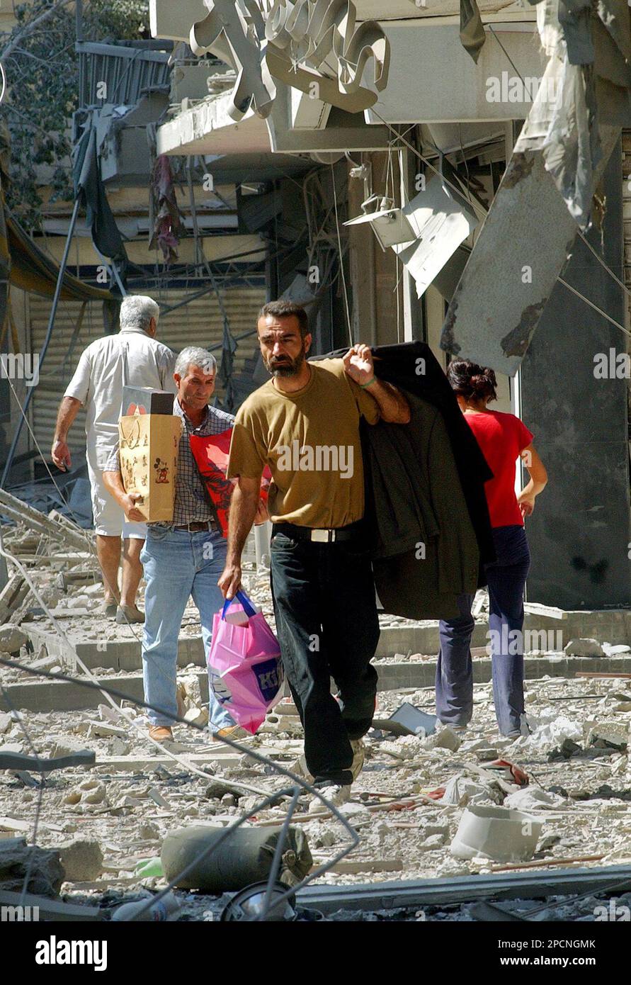 Lebanese civilians carry their belongings as they walk on the rubble of ...