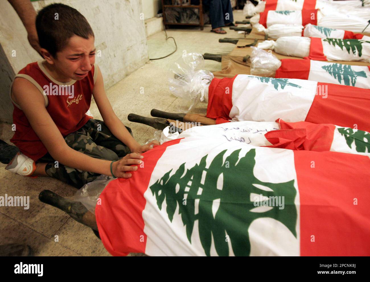 A young Lebanese mourns over the bodies of his relatives, draped in ...