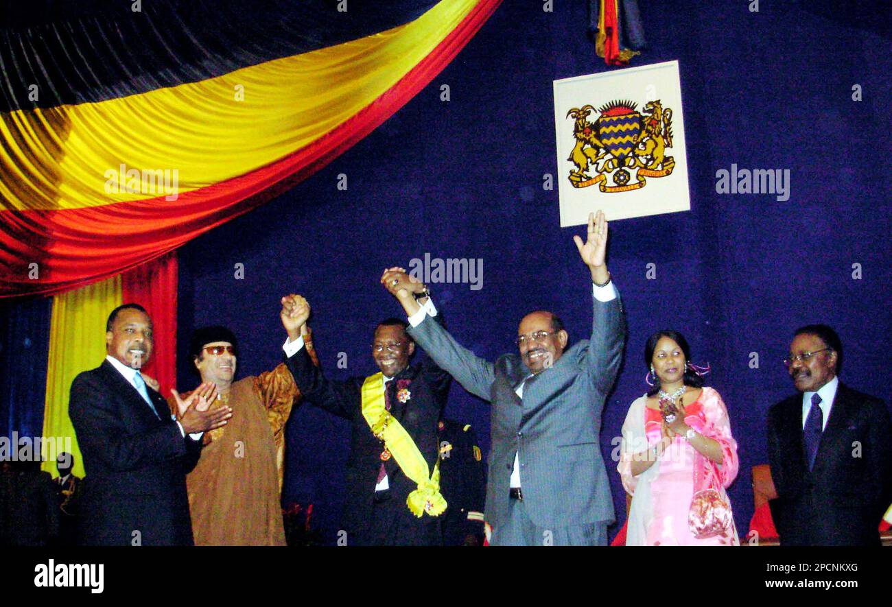 Chadian President Idriss Deby, wearing yellow sash, raises the hand of ...