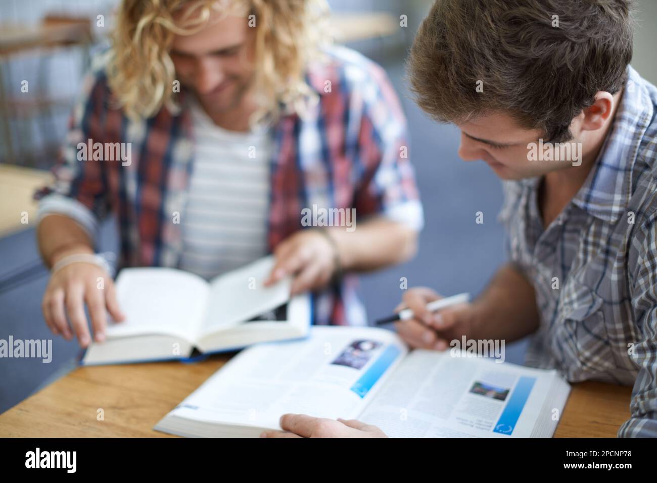 Combining their assignment research. two male students studying ...