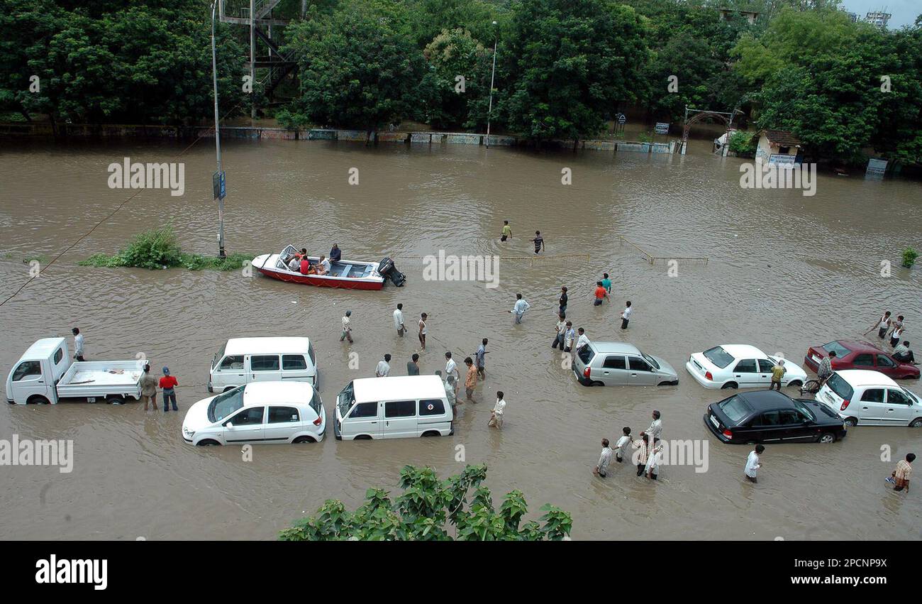 People wade through floodwaters at Surat, in the western Indian state ...