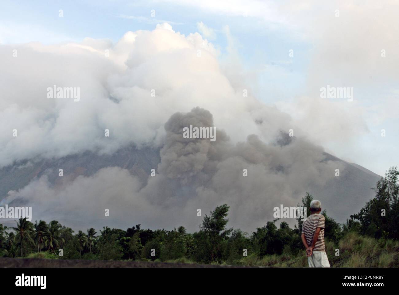 A resident watches as a brownish mushroom cloud of volcanic ash is ...