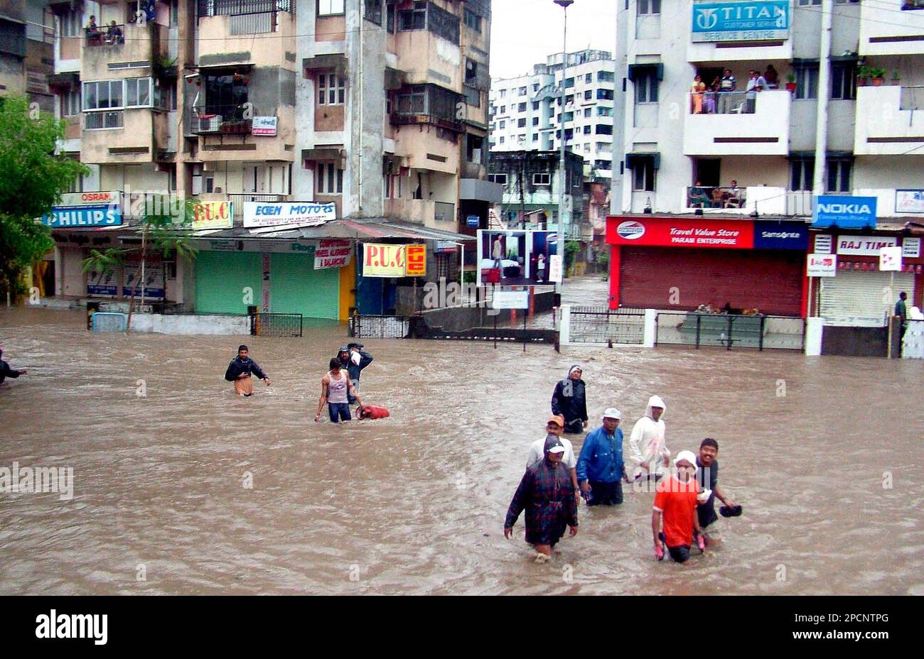 People walk through a flooded street in Surat, in the western Indian ...