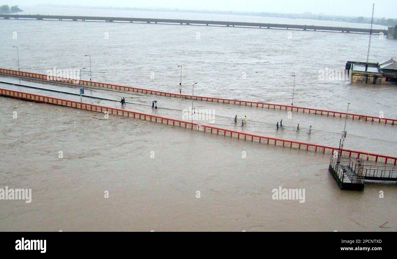 People cross a flooded bridge of the River Tapti, in Surat, in the ...
