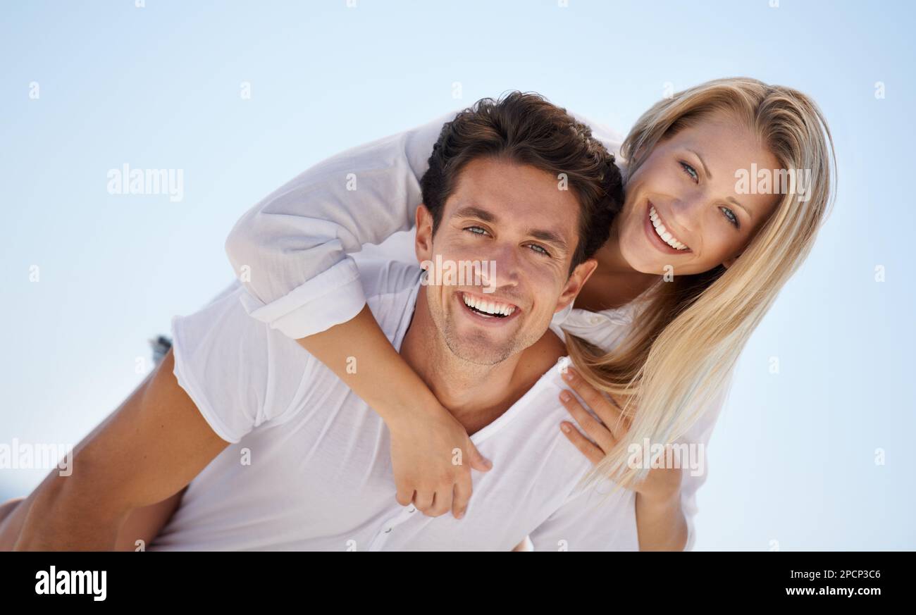 Playful summer romance. A handsome young man giving his girlfriend a ...