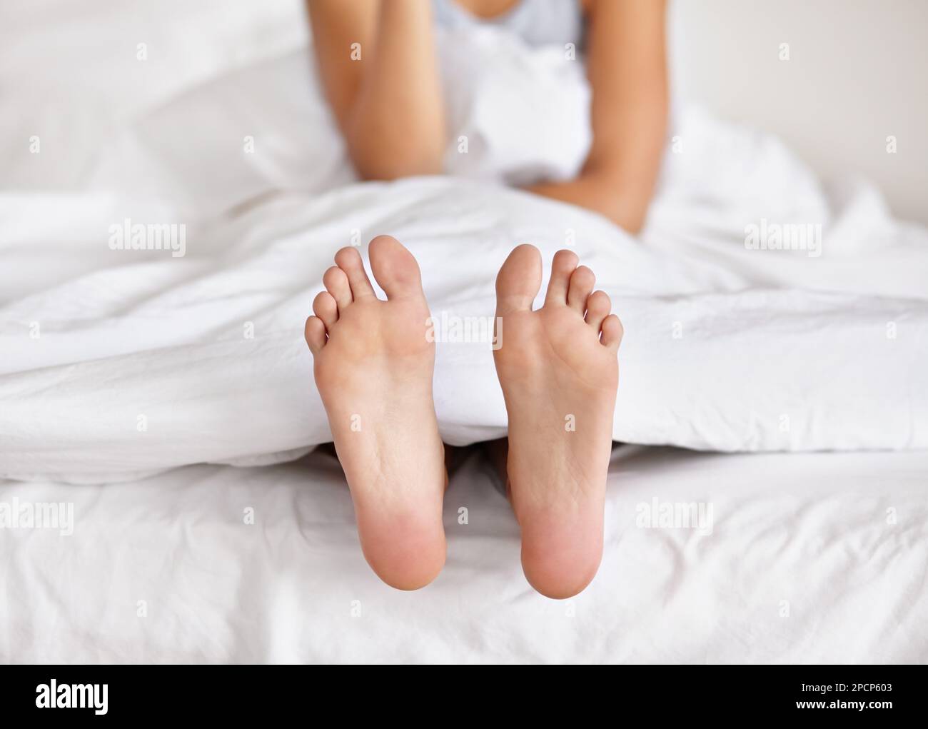 Wiggling toes of wakefulness. a pair of womans feet poking out from ...