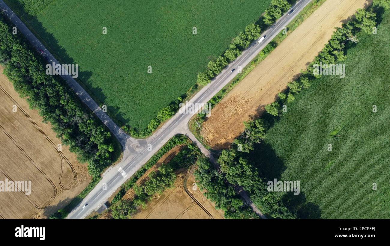 Automobile asphalt road with cars driving along it between agricultural ...