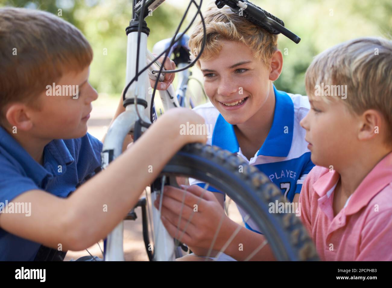 Fixing up the wheel. Happy young boys playing outside with a bicycle ...