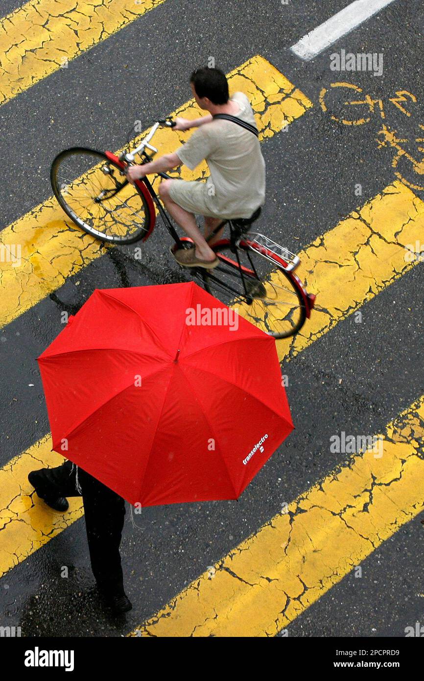 Ein Mann mit Regenschirm rennt ueber einen Fussgaengerstreifen ...