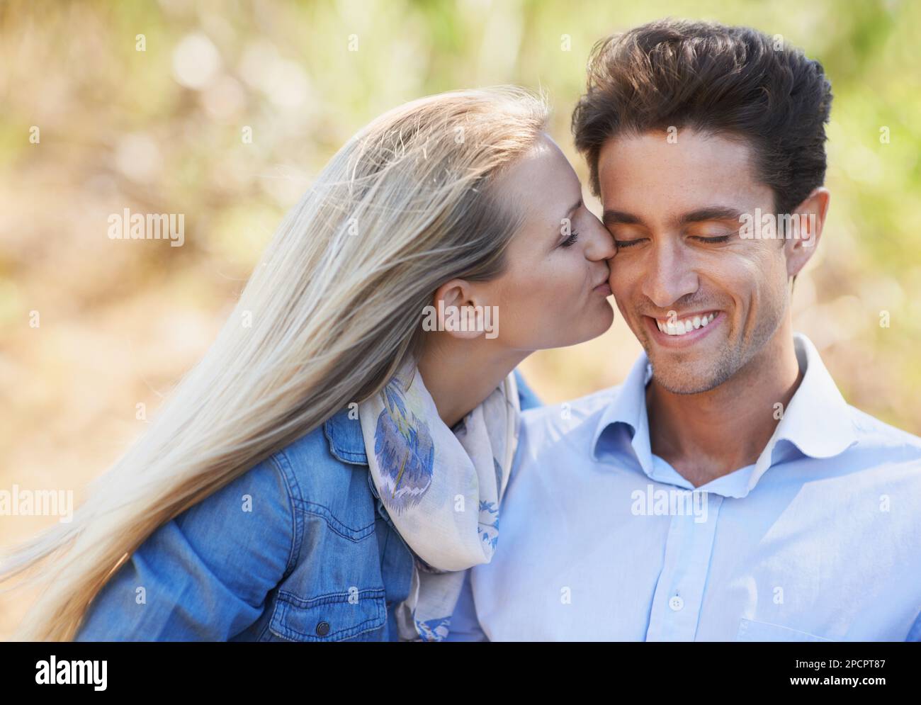 Intimate moments. A beautiful young woman kissing her boyfriend on the cheek Stock Photo - Alamy
