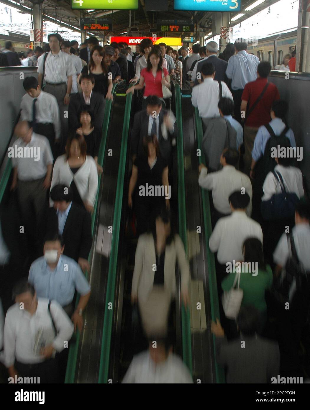 Commuters pack escalators at a railway station in Tokyo Friday morning ...