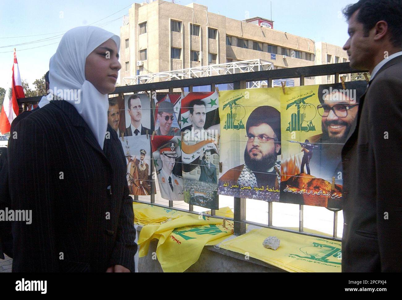 Syrians walk near portraits of Syrian President Bashar Assad, left, and Lebanese Hezbollah ...