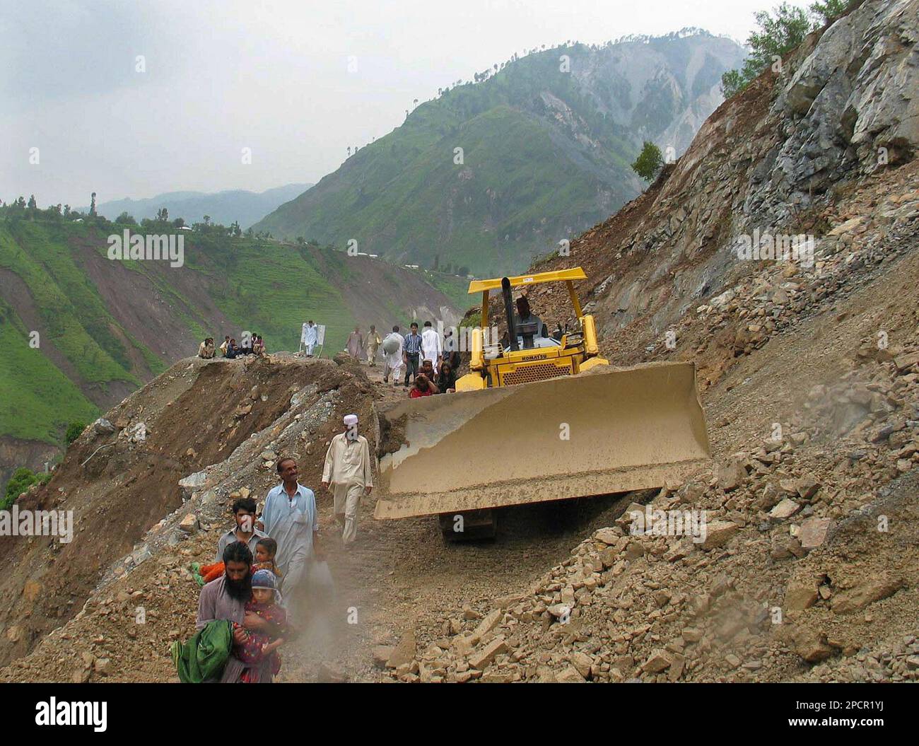 Kashmiri villagers walk on an alternate road paved by bulldozer along a ...