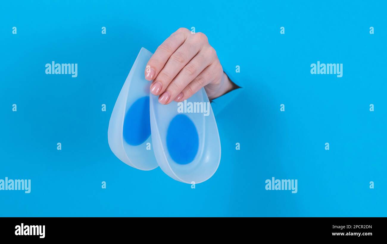 Woman holding orthopedic silicone heel pads. A woman's hand sticks out ...