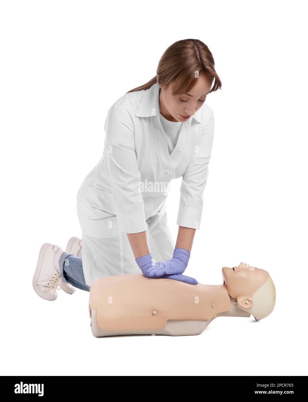 Doctor in uniform practicing first aid on mannequin against white ...