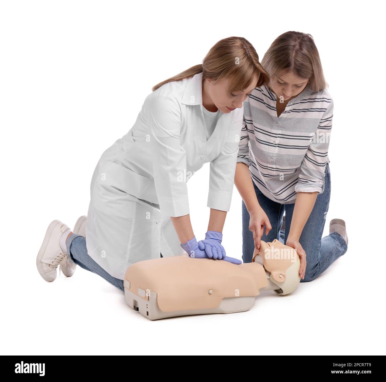 Doctor in uniform demonstrating first aid on mannequin against white ...
