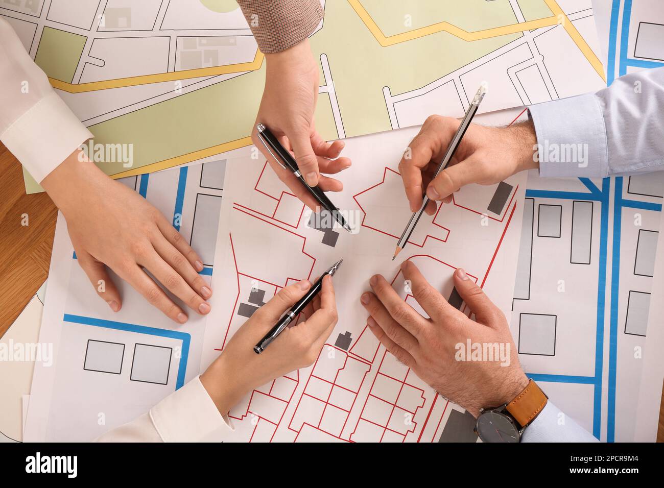 Professional cartographers working with cadastral map at table, top ...
