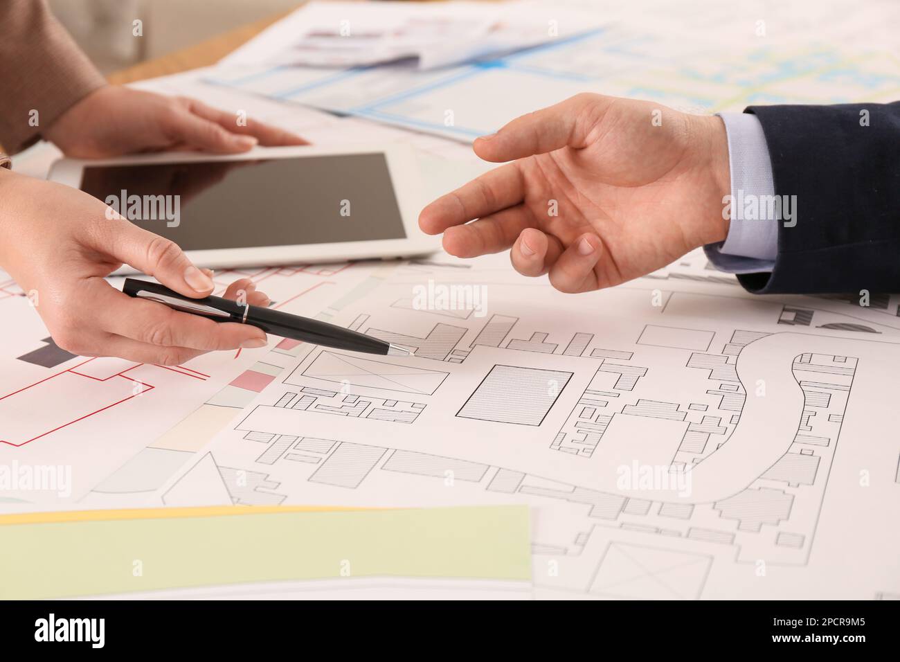 Professional cartographers working with cadastral map at table, closeup ...