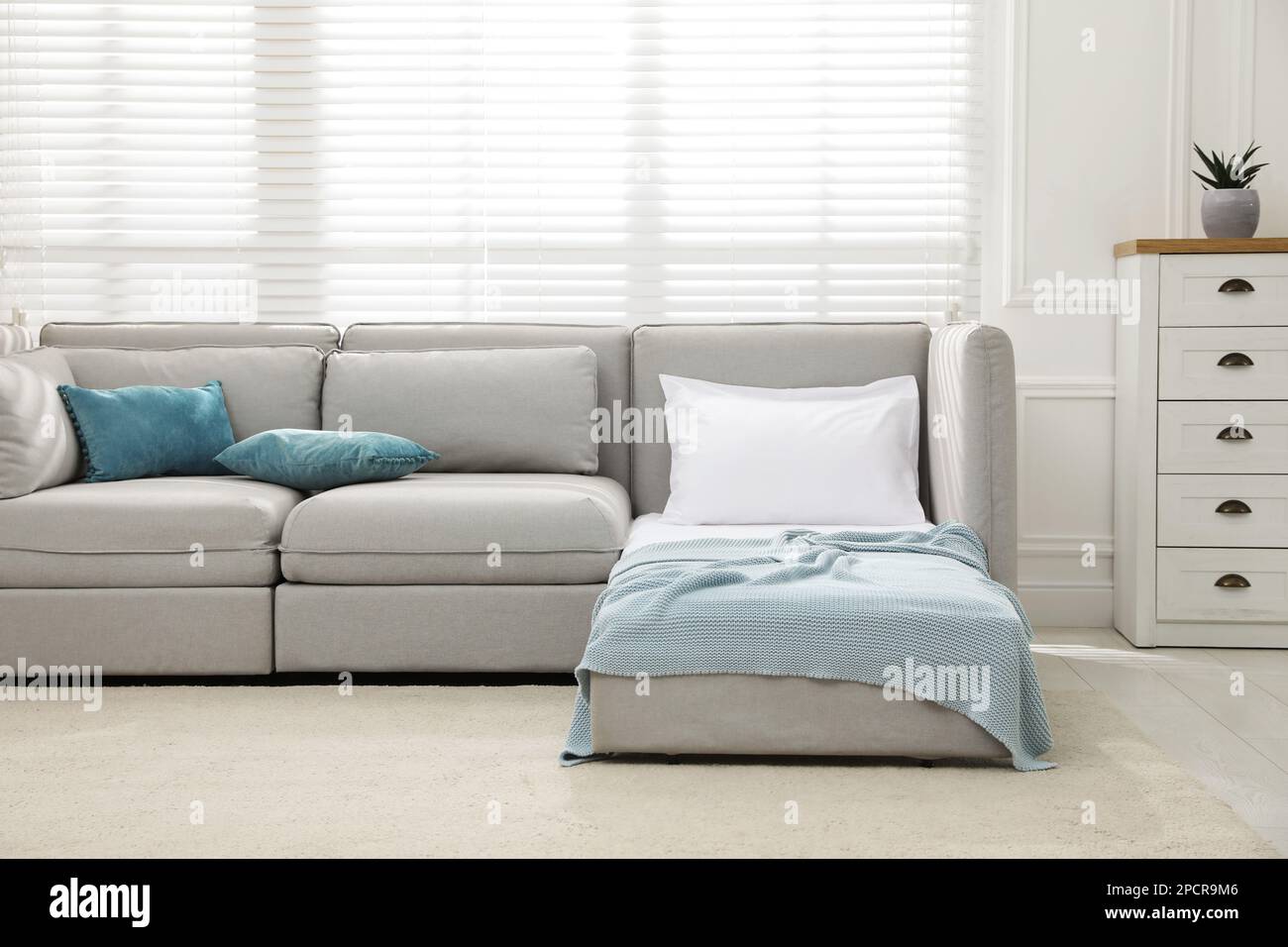 Stylish room interior with sleeper sofa near window. Additional place ...