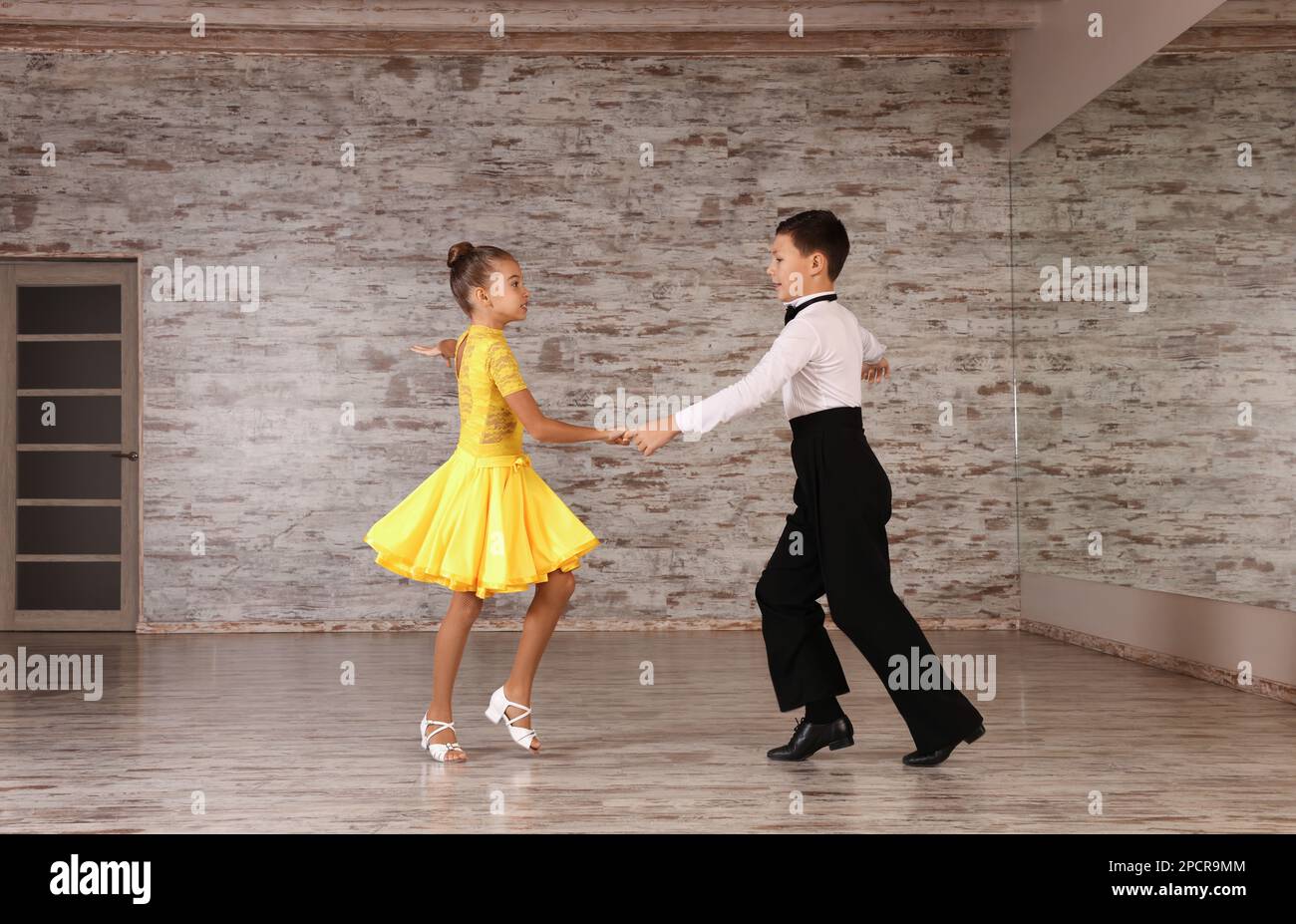 Beautifully dressed couple of kids dancing together in studio Stock ...