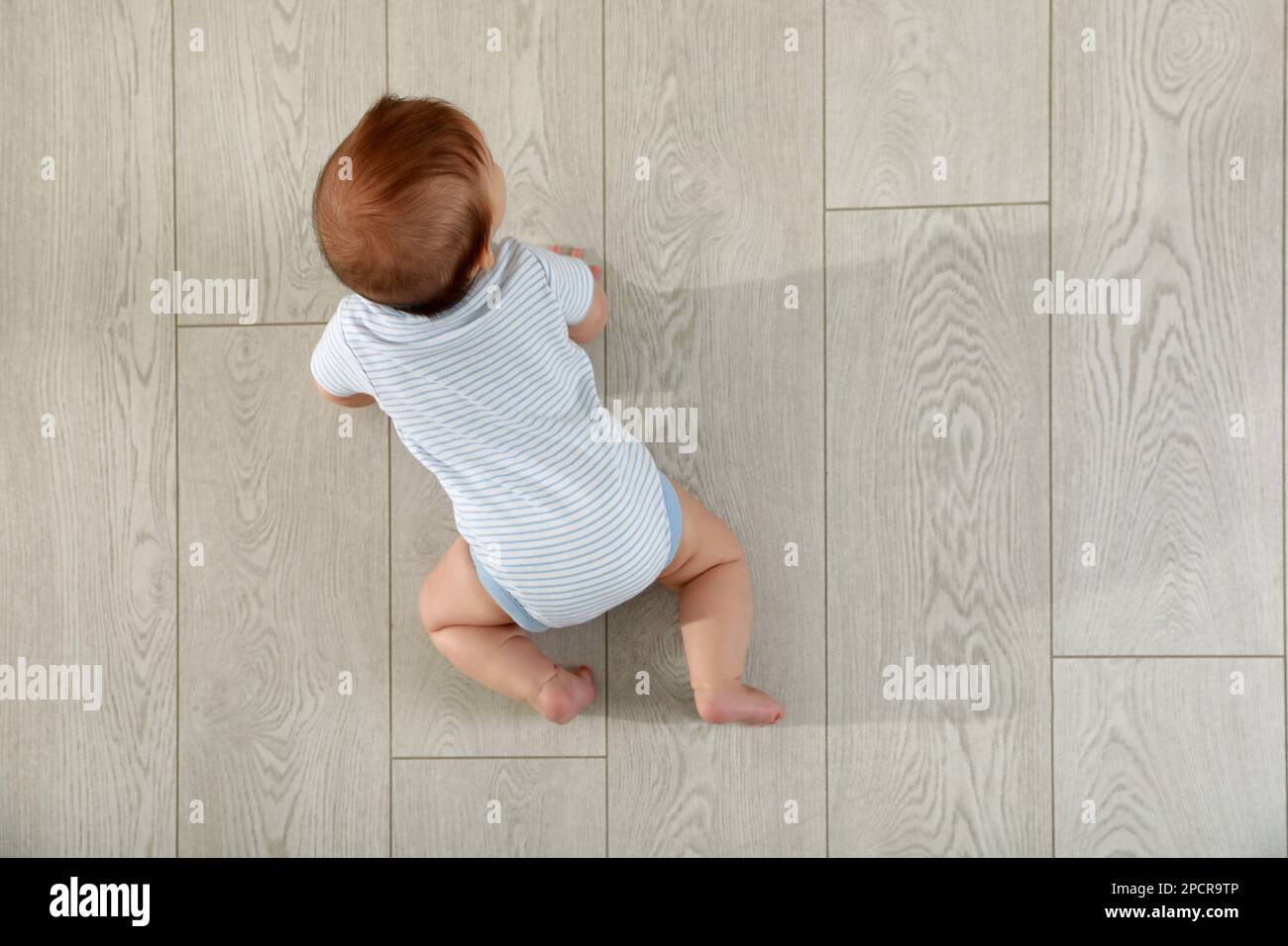 Cute baby crawling on floor, top view Stock Photo - Alamy