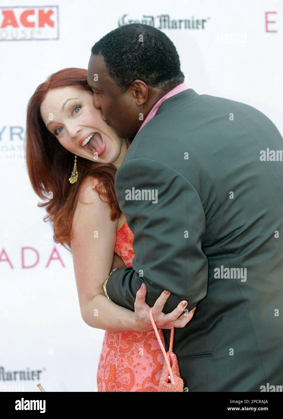 Actress Amy Yasbeck, left, gets a kiss from Rodney Peete as they pose ...