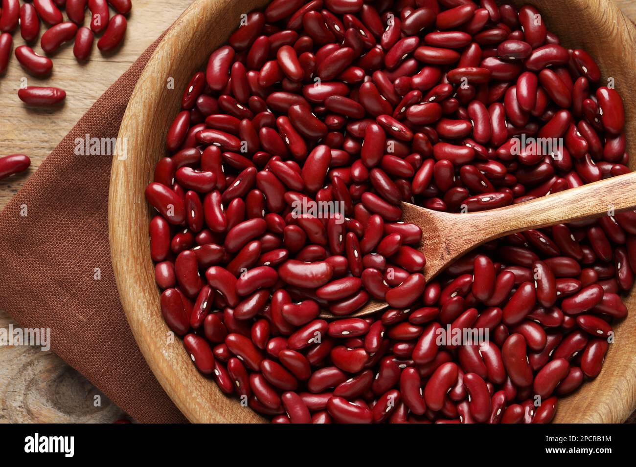 Raw red kidney beans with wooden bowl, spoon and napkin on table, top ...