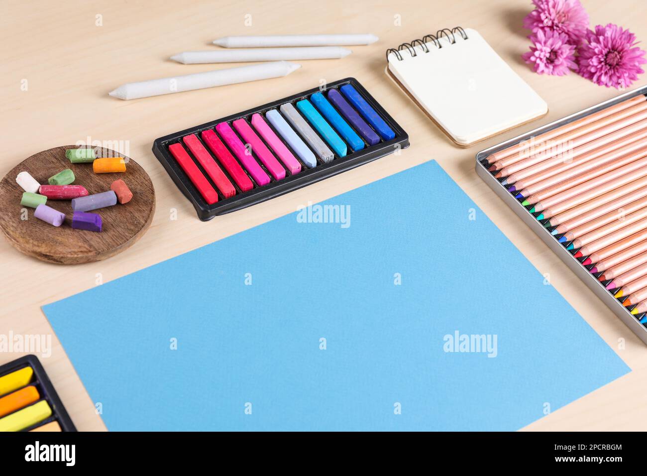 Blank paper, soft pastels and drawing pencils on wooden table at artist ...