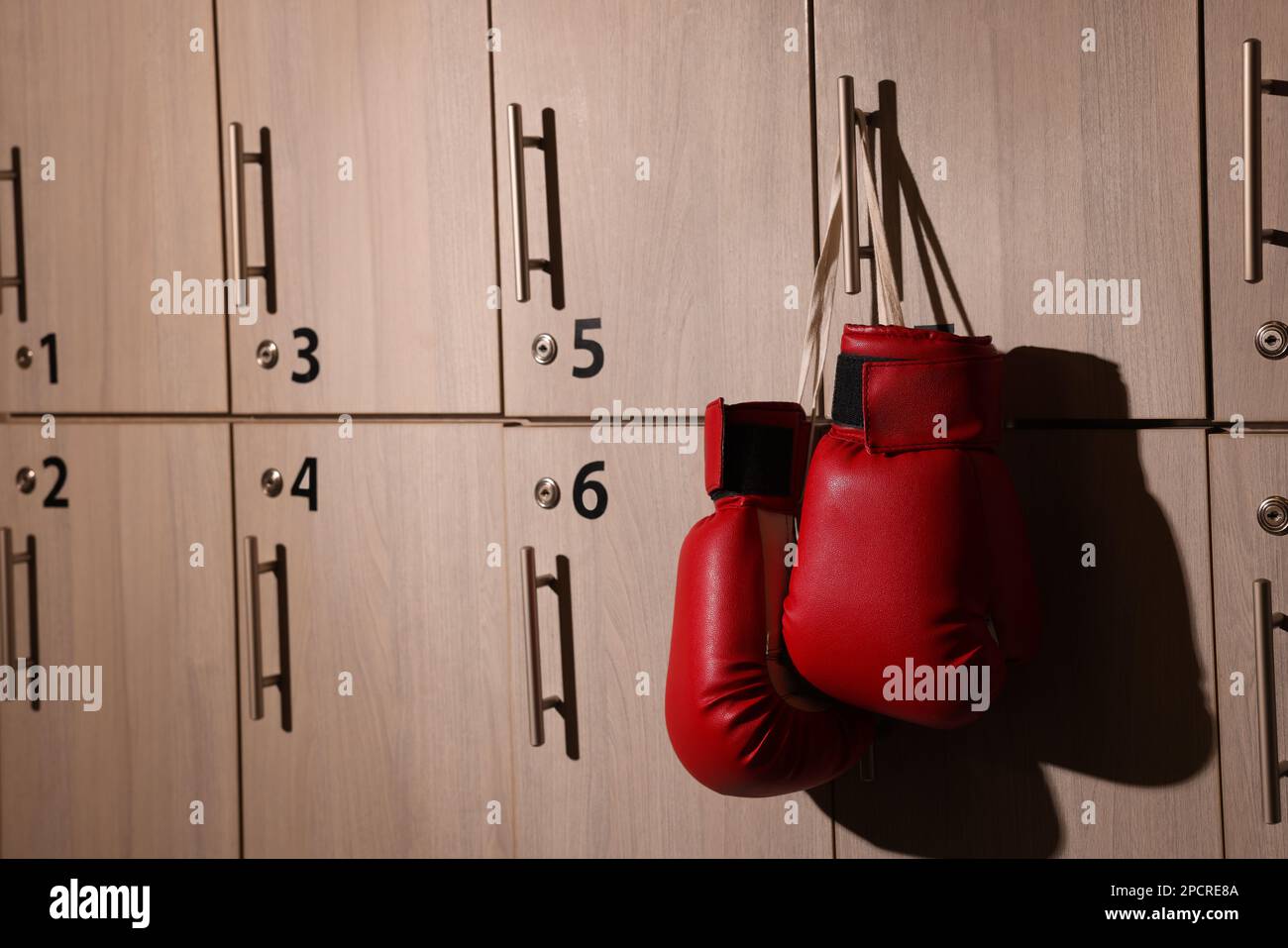 Red boxing gloves hanging on locker door in changing room. Space for ...